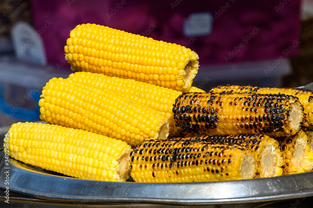 Freshly boiled and grilled organic sweet corn in display for sale at a ...