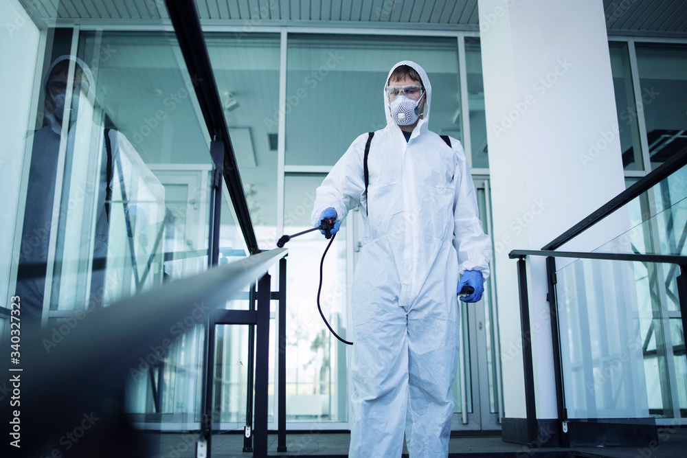 Shot of male person in white chemical protection suit doing ...