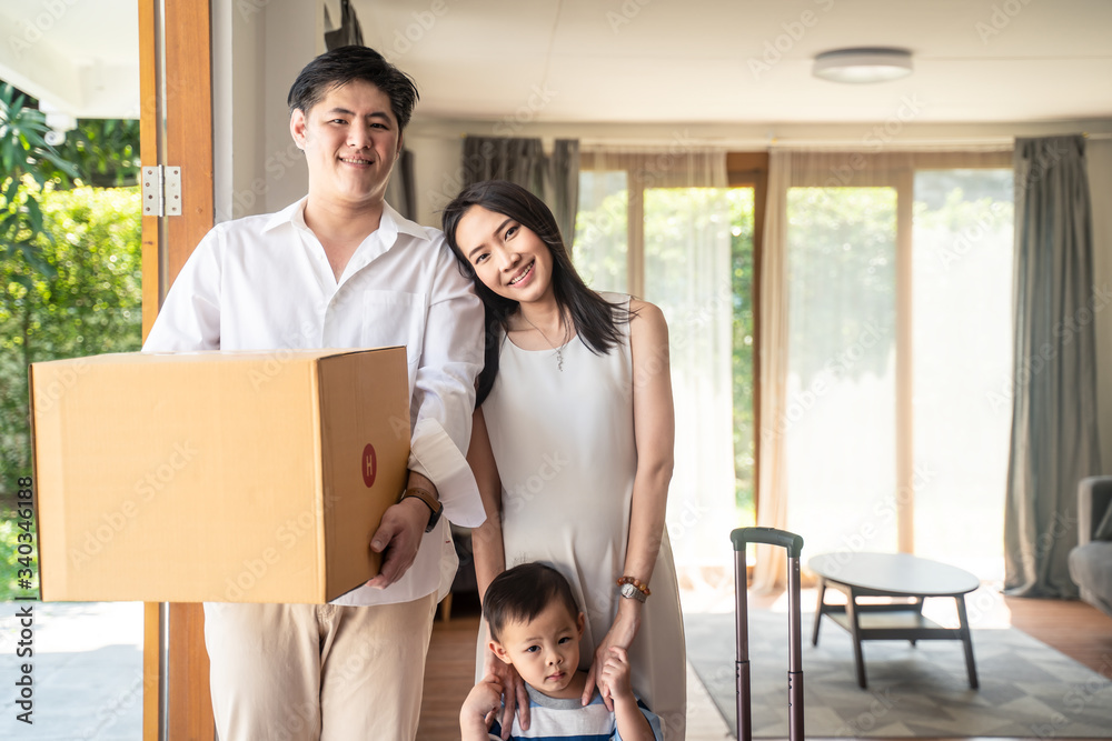 Asian family moving to new house, father holding big box standing near ...