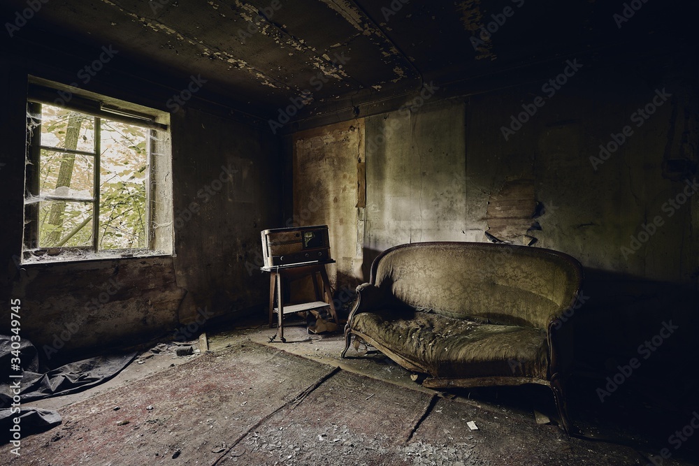Abandoned room with a broken sofa on an aged floor and with a broken ...