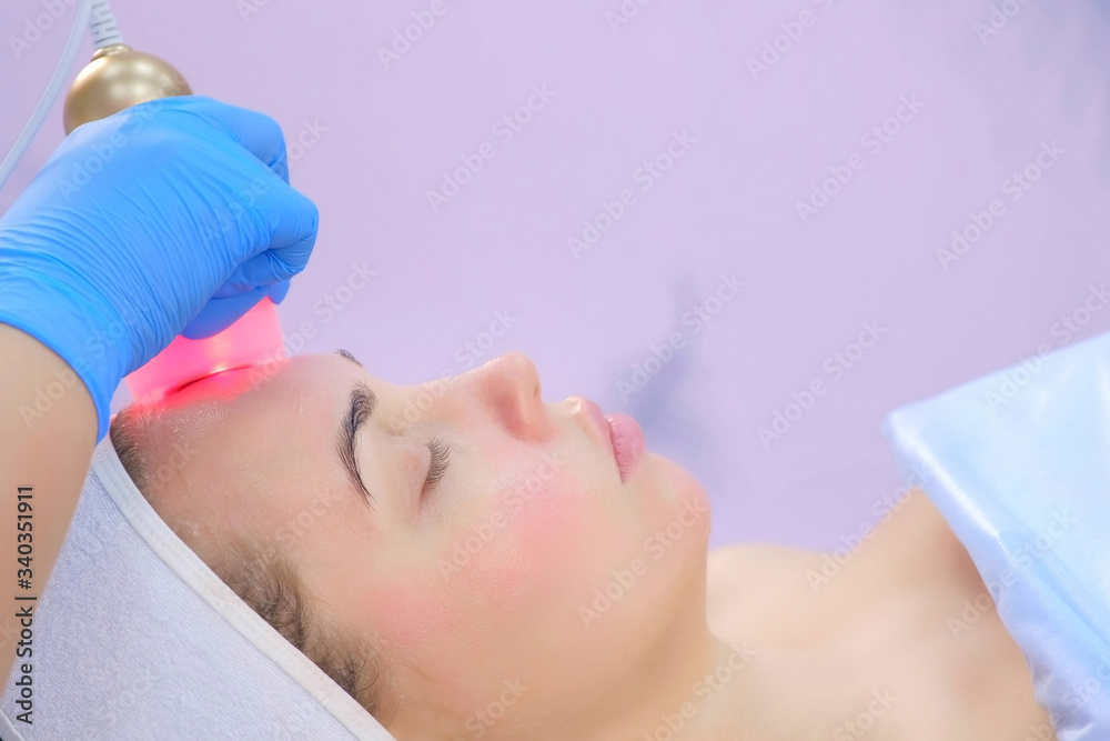 Cosmetologist doctor making phonophoresis procedure on woman face with ...
