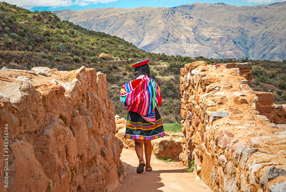 Quechua Indigenous Woman in traditional clothes walking along ancient ...