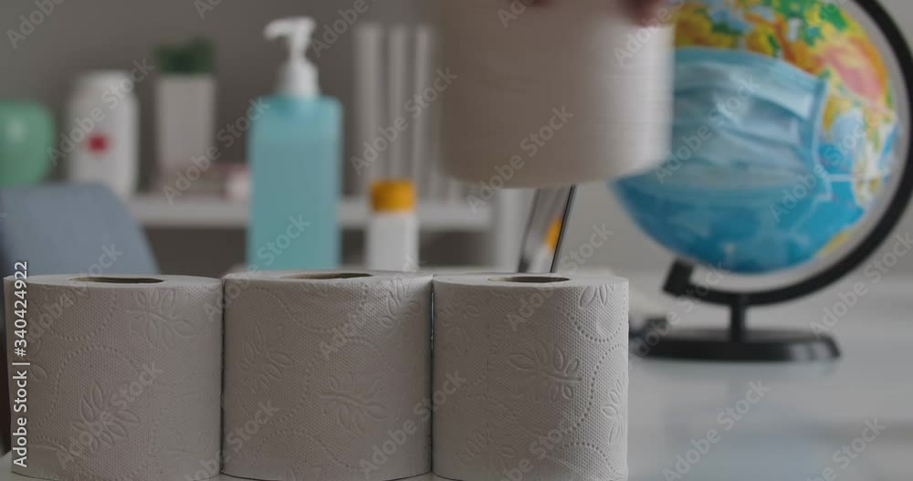 Close-up of male Caucasian hand putting rolls of toilet paper on the ...