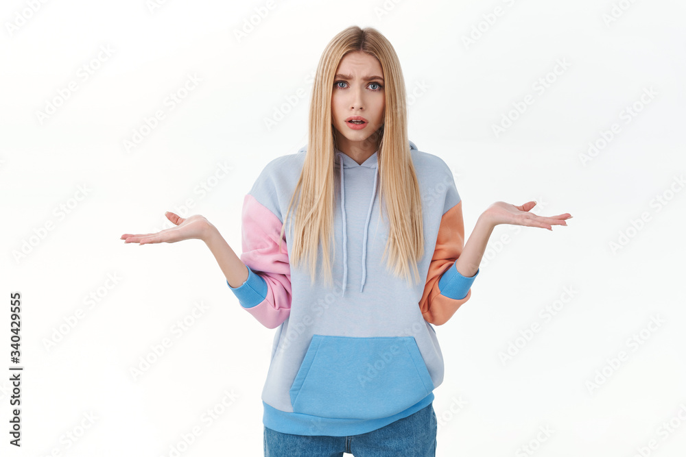 Puzzled and confused blond girl in hoodie, shrugging with hands spread ...