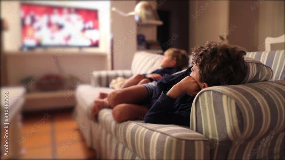 Kids in front of TV screen watching movie. Children lying on sofa couch ...