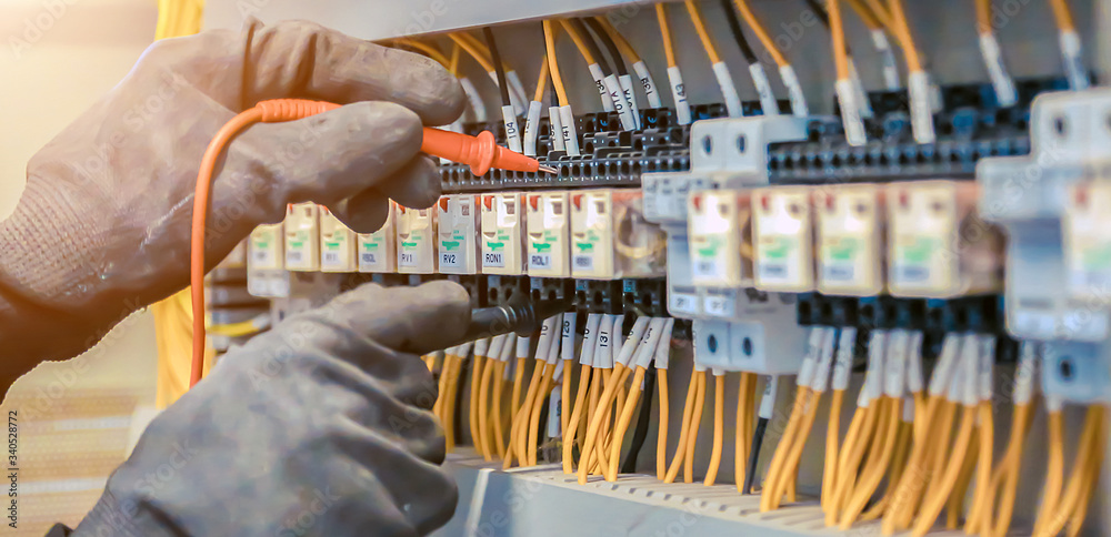 Electrical engineer using digital multimeter to check current voltage ...