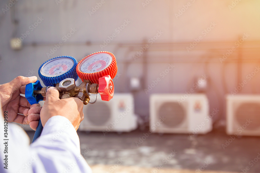 Technician using measuring equipment for filling air conditioners and ...