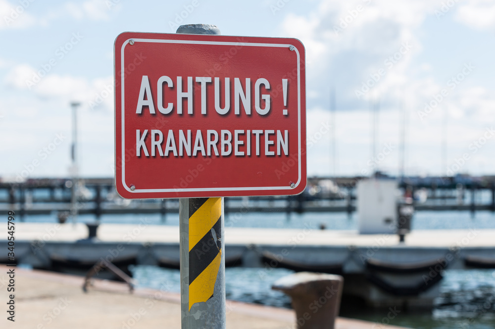 a red sign "Attention! Crane work" (German "Achtung! Kranarbeiten") in ...