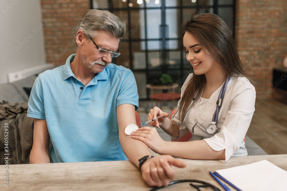 Nurse injecting with syringe to patient's arm drawing blood sample for ...