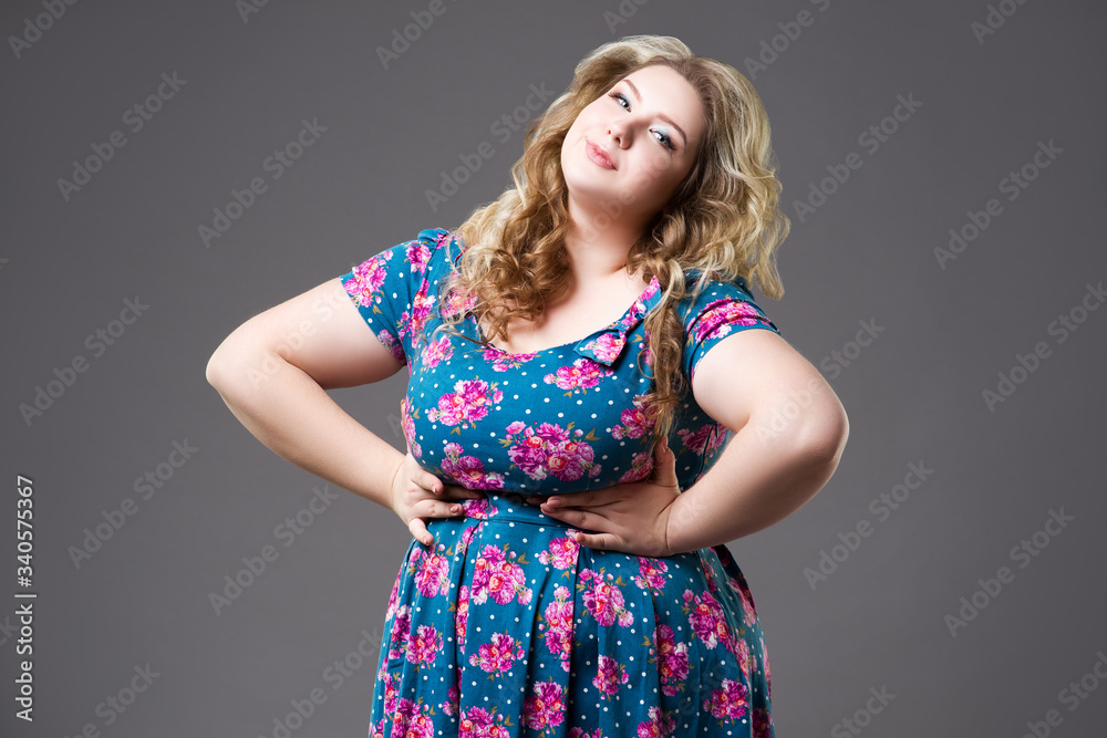Plus size fashion model in floral dress, fat woman on gray background ...