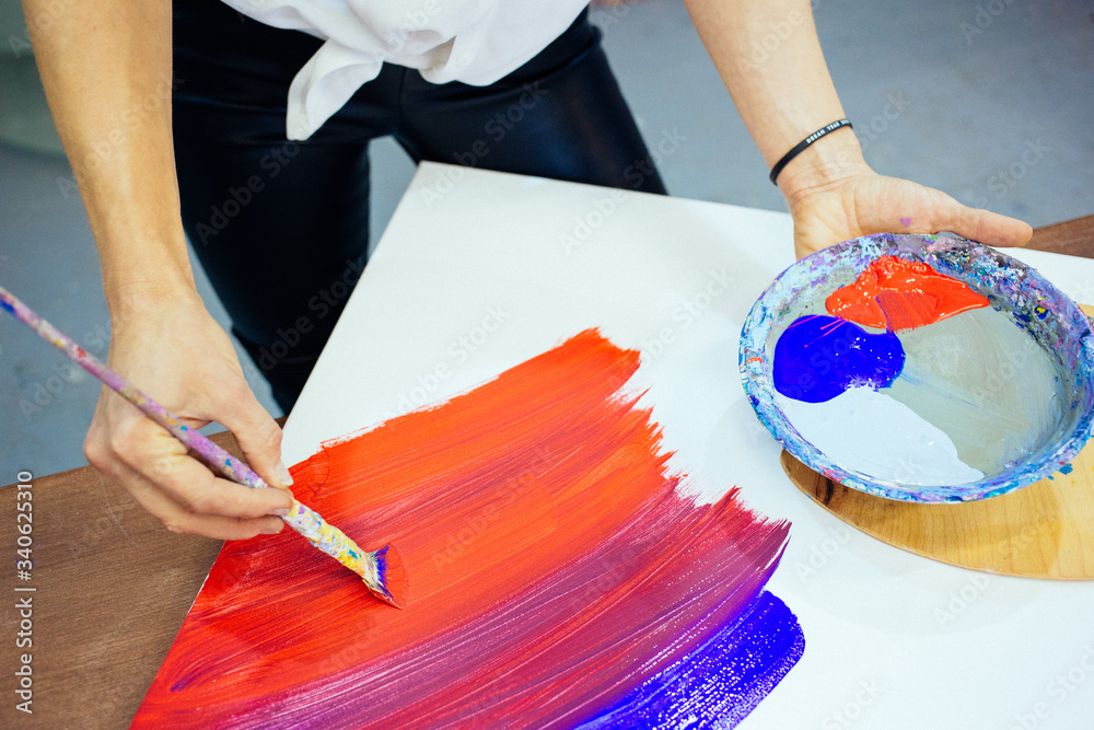 The artist paints a new picture, she uses red and blue colors of oil ...