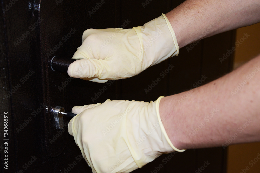 The man put on rubber gloves and tries to open the front door. One hand ...