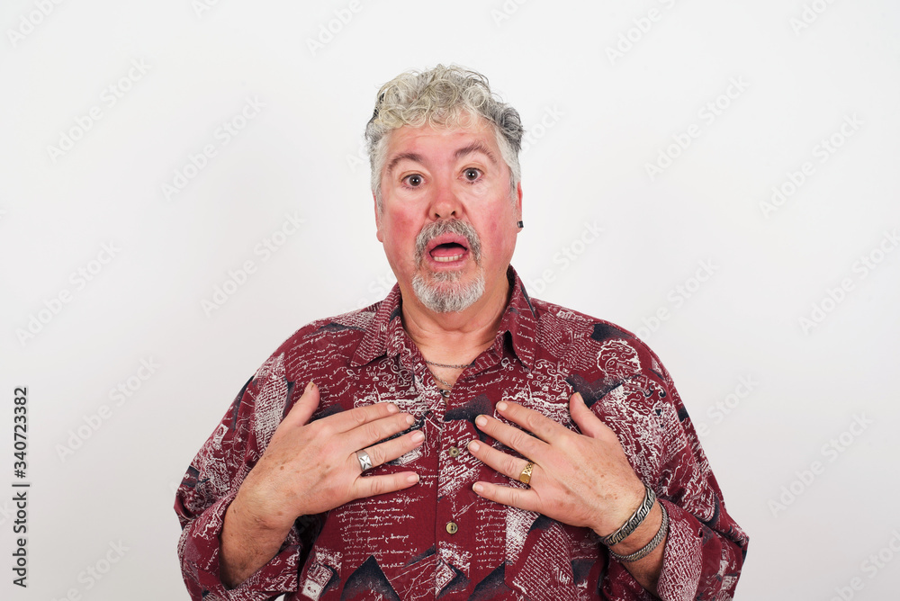 Shocked scared beautiful young man keeps hands on chest, mouth widely ...