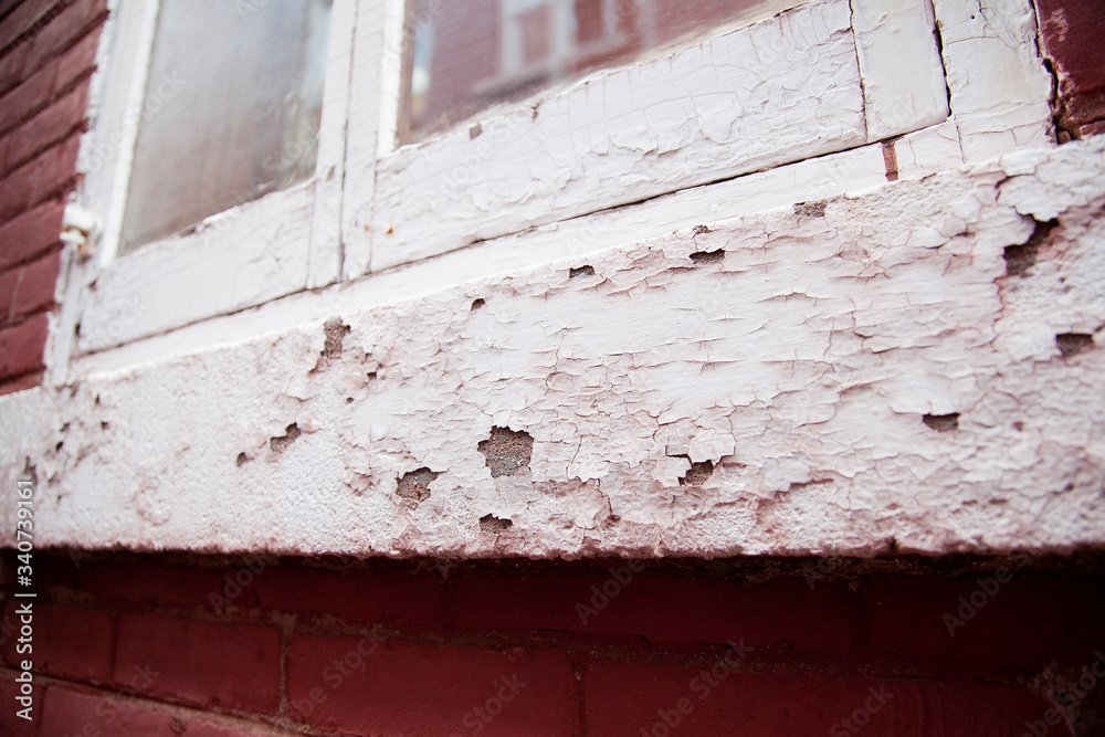 View of an old red and white building window with flaky chipped paint ...