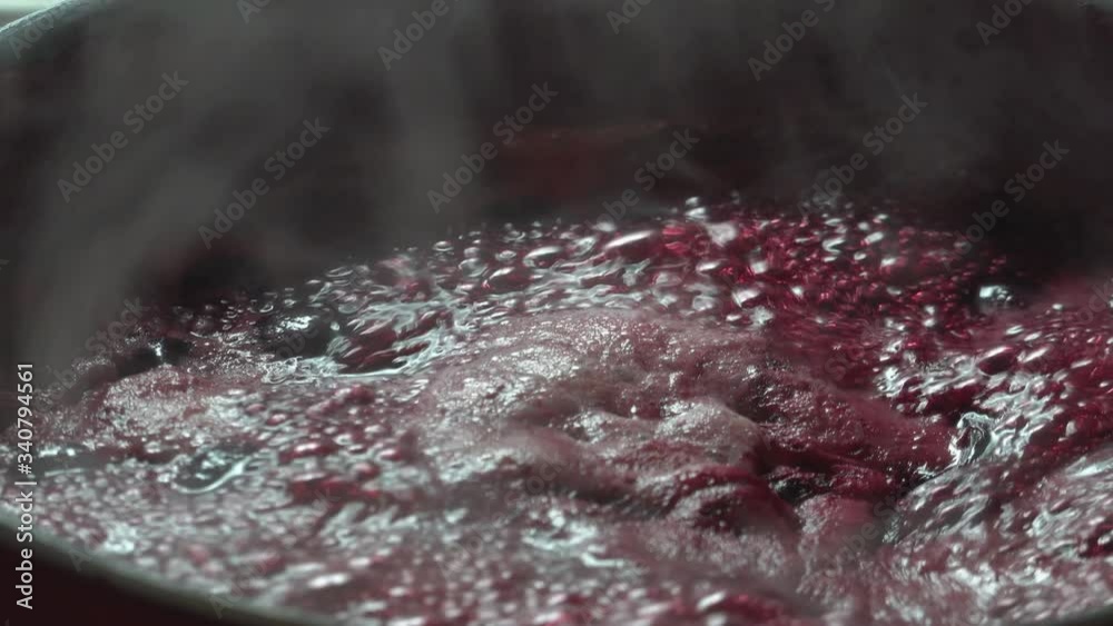 Cooking delicious red fruit jam, mixing and kneading. Close up ...