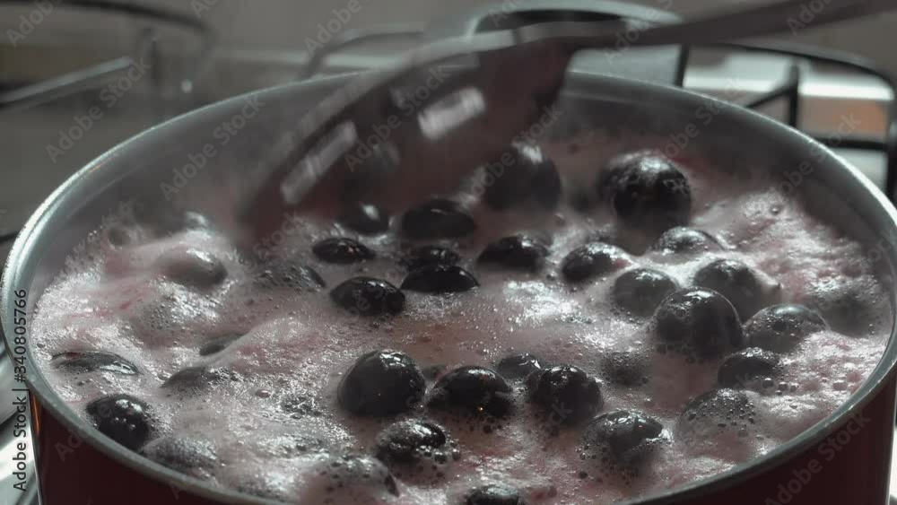 Cooking delicious red fruit jam, mixing and kneading. Close up ...