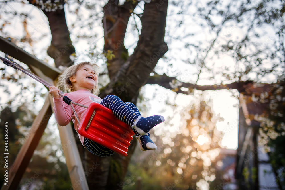 Happy beautiful little toddler girl having fun on swing in domestic ...