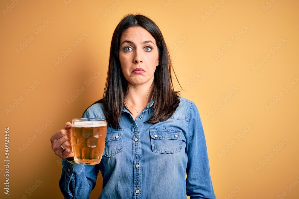Young woman with blue eyes drinking jar of beer standing over isolated ...