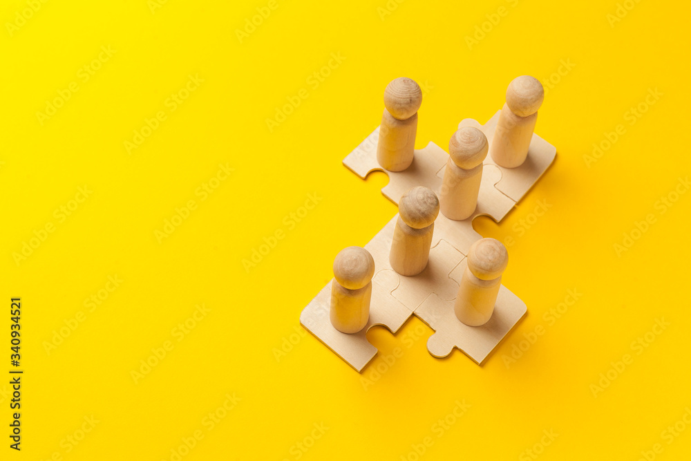 Wooden figures on puzzles on yellow background as a symbol of team ...