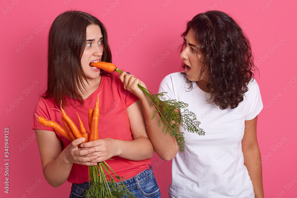 Horizontal shot of shocked emotional female having carrot in mouth ...