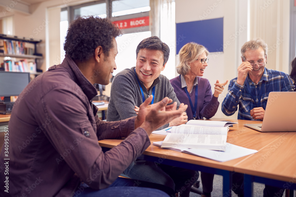 Teacher With Group Of Mature Adult Students In Class Sit Around Table ...