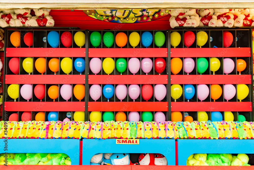 balloons and prizes at a dart throwing game booth at a carnival, fair ...