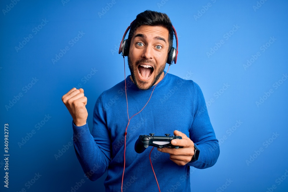 Young handsome gamer man with beard playing video game using joystick ...