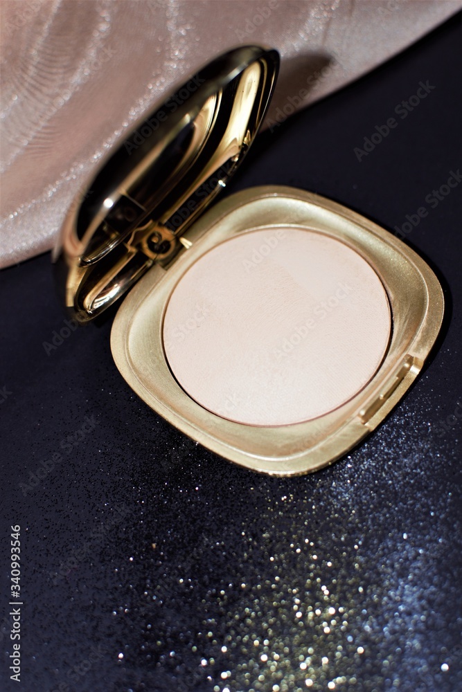 Compact face powder in gold powder case isolated on black and gold ...