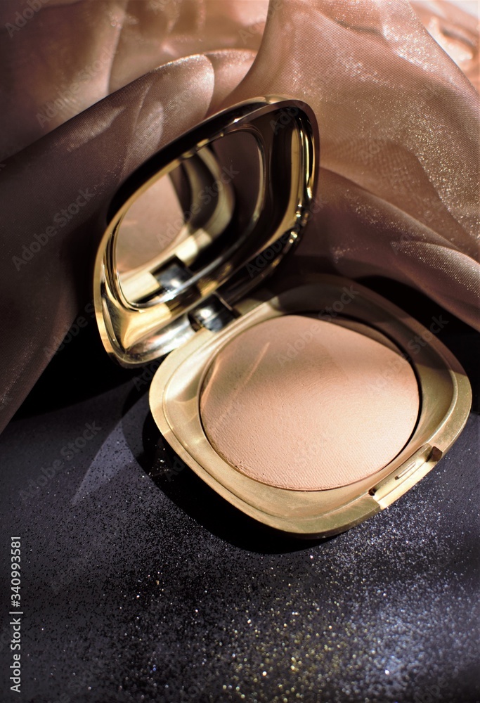 Compact face powder in gold powder case isolated on black and gold ...