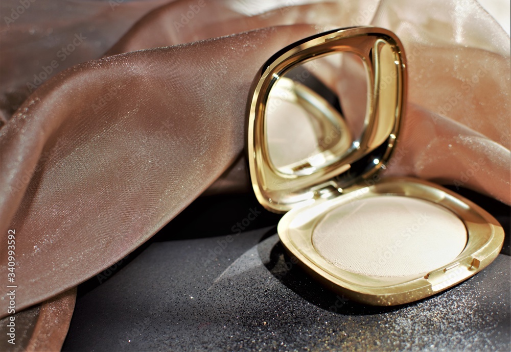 Compact face powder in gold powder case isolated on black and gold ...
