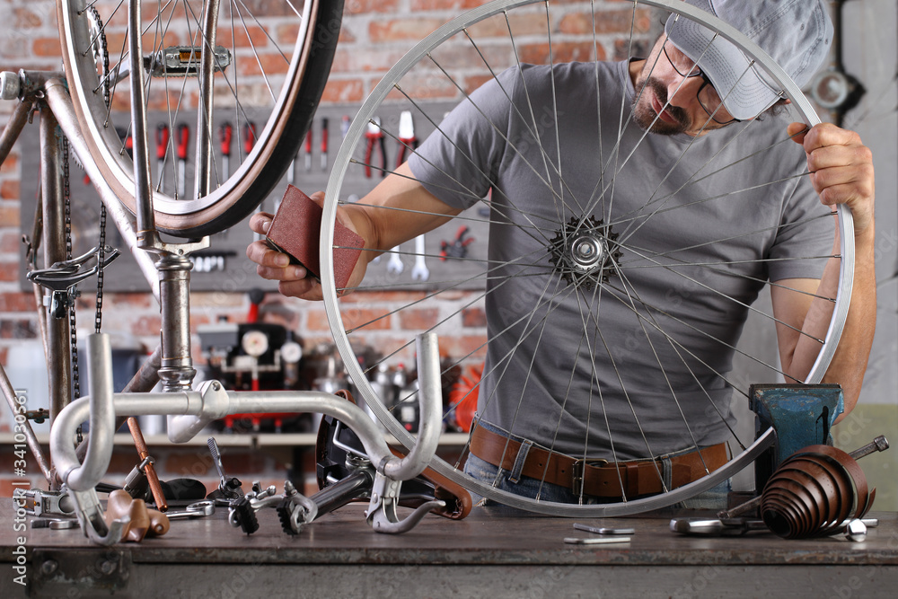 man repair the vintage bicycle in garage workshop on the workbench with ...