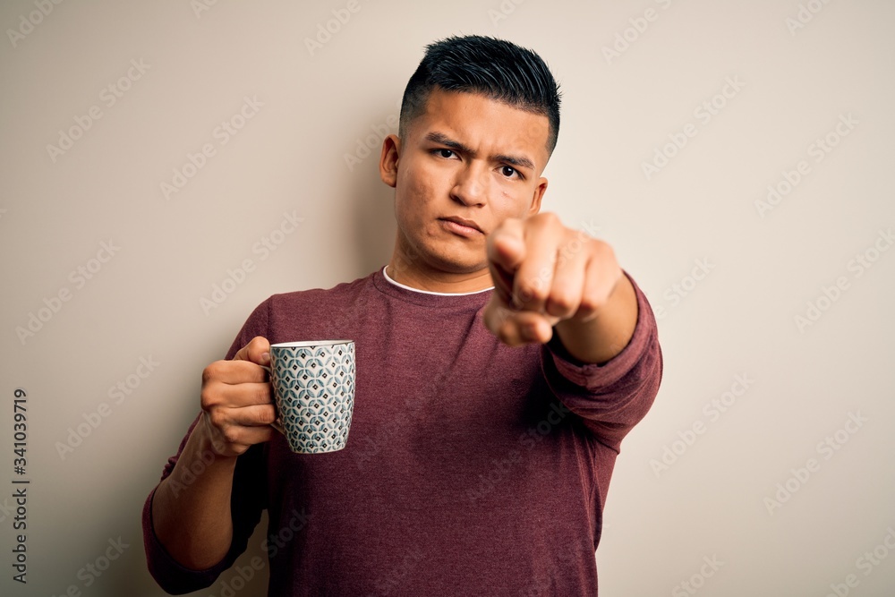 Young handsome latin man drinking cup of coffee over isolated white ...