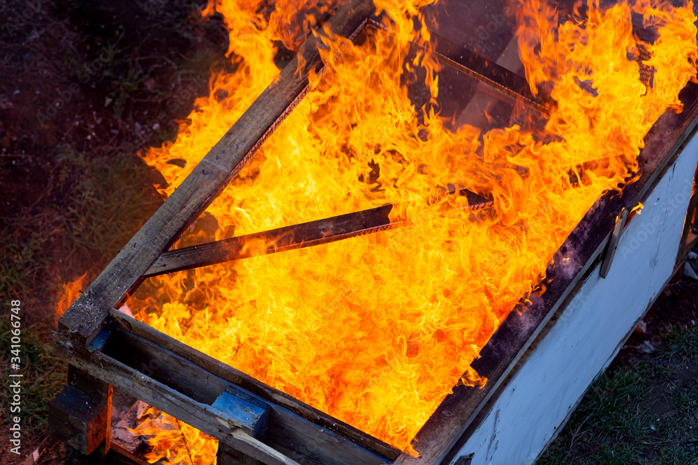 Fire coils over a burnt building. A pile of coals at the site of a ...
