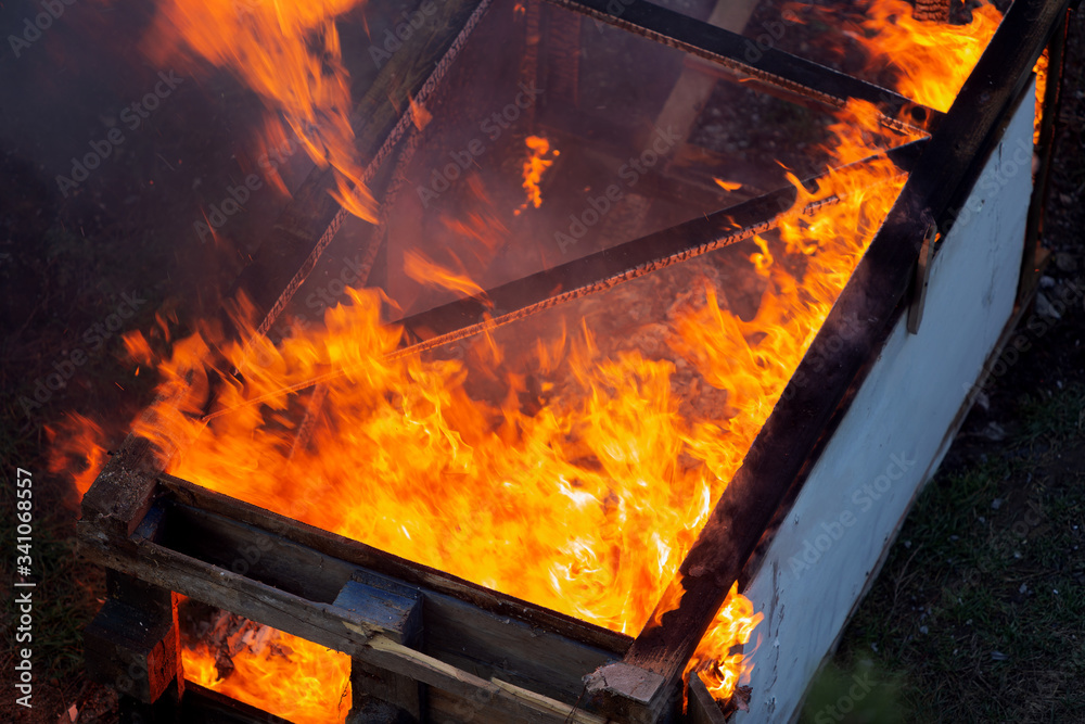 Fire coils over a burnt building. A pile of coals at the site of a ...