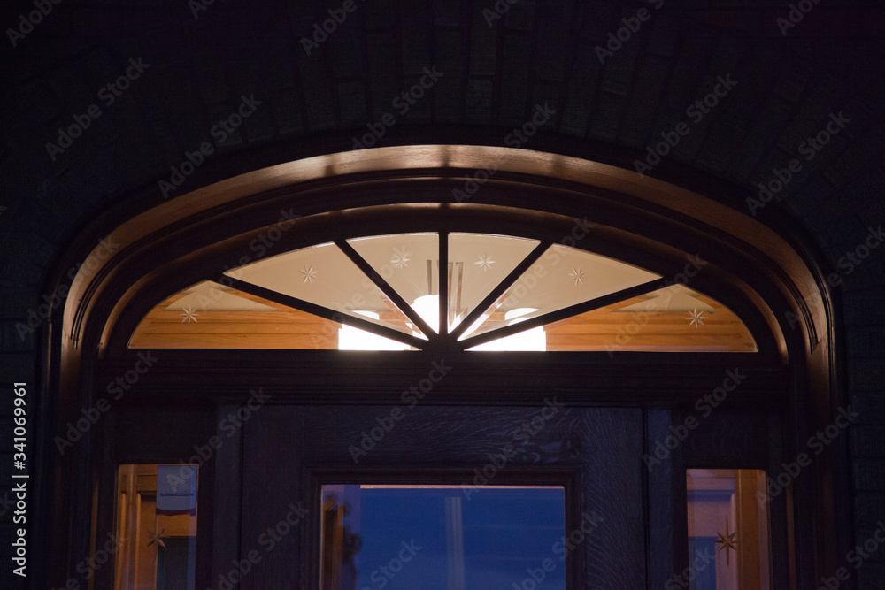 Beautiful illuminated brown wood arched window at twilight with a ...