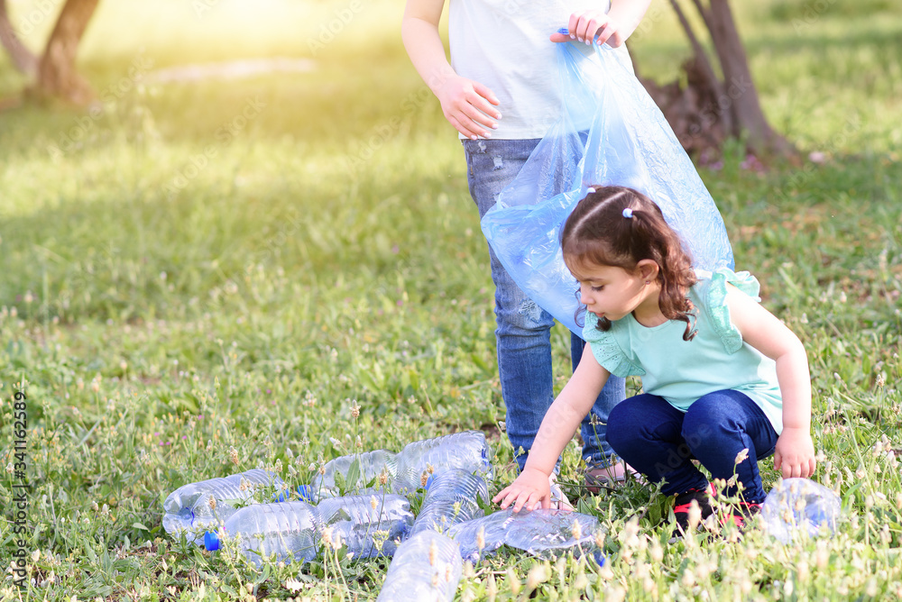 Cute little girls cleaning up plastic litter on grass. Children ...