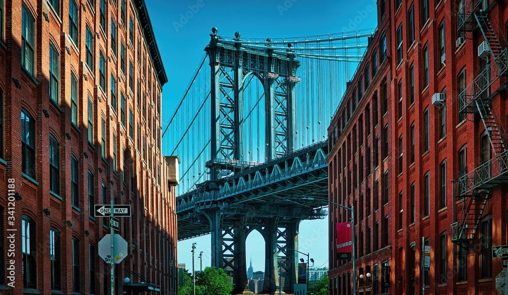 Manhattan Bridge seen from a narrow alley enclosed by two brick ...