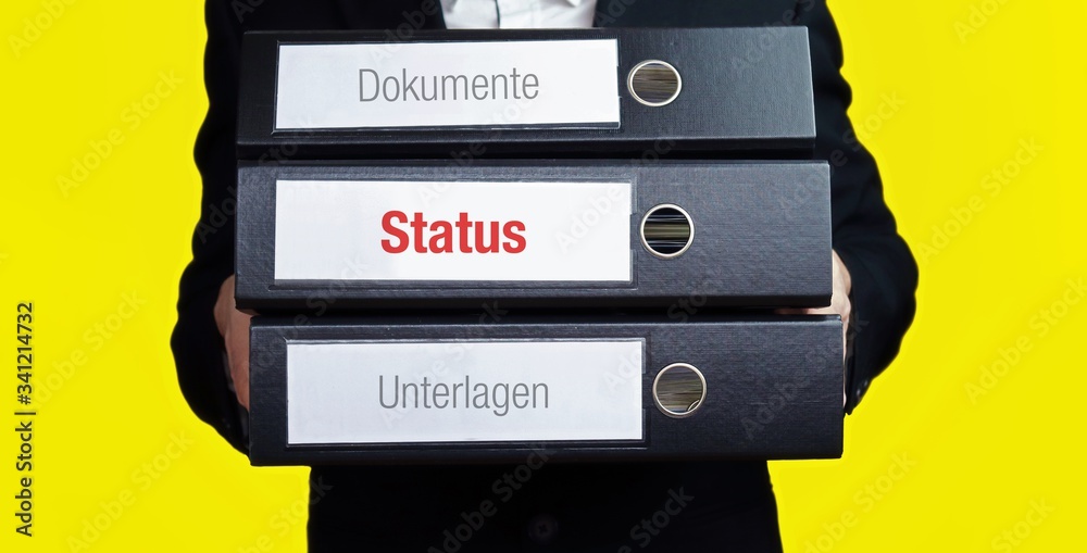 Status – Finanzen/Wirtschaft. Mann trägt einen Stapel Aktenordner. Ein ...