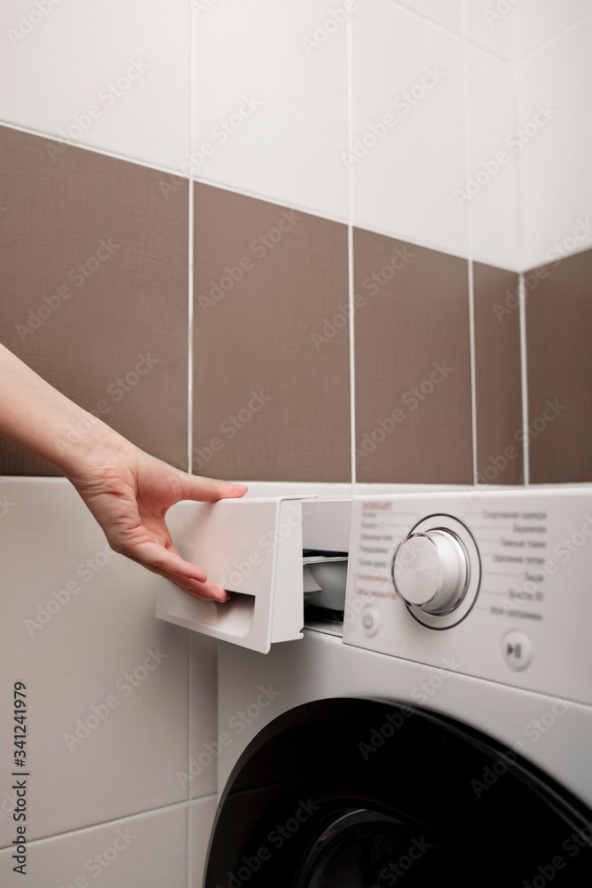 Housewife woman in the laundry room, opens a container for washing ...