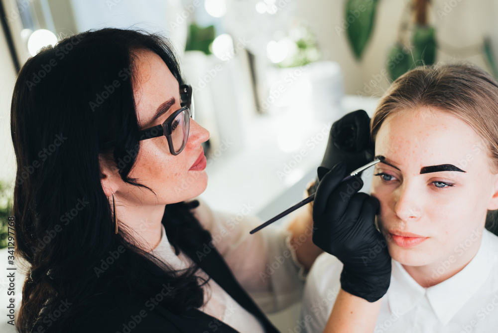 Dyeing and shaping of eyebrows. girl in a beauty salon.eyebrow coloring ...