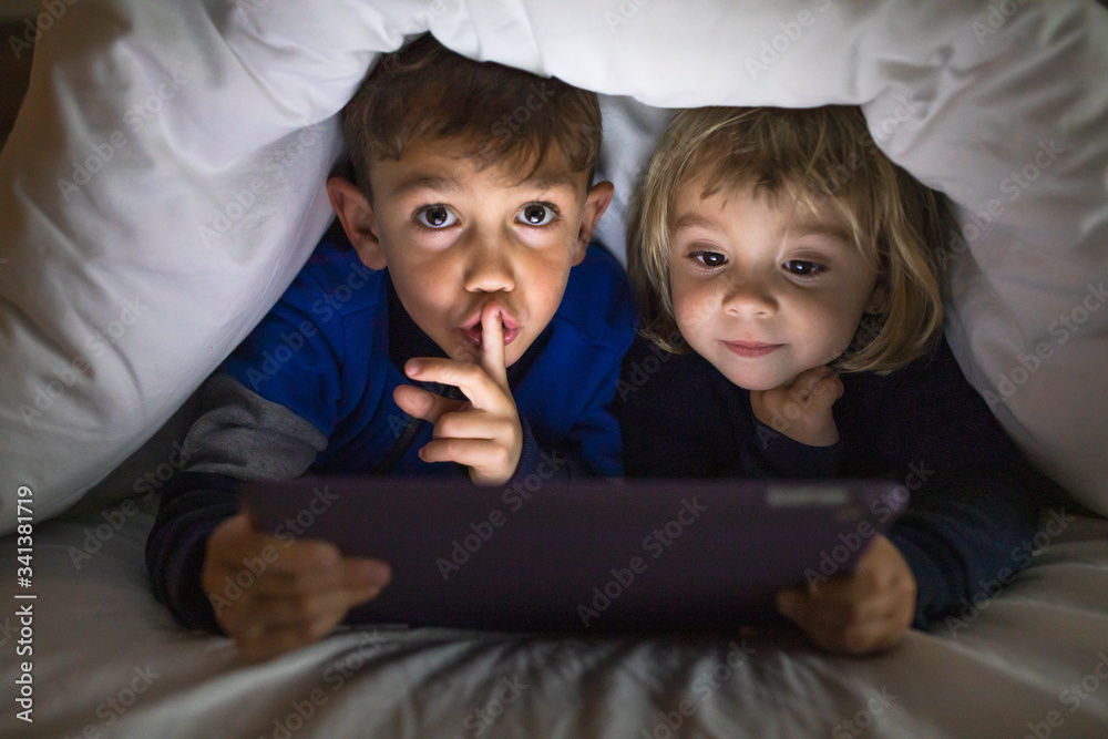 Portrait of brother and little sister lying side by side under a ...