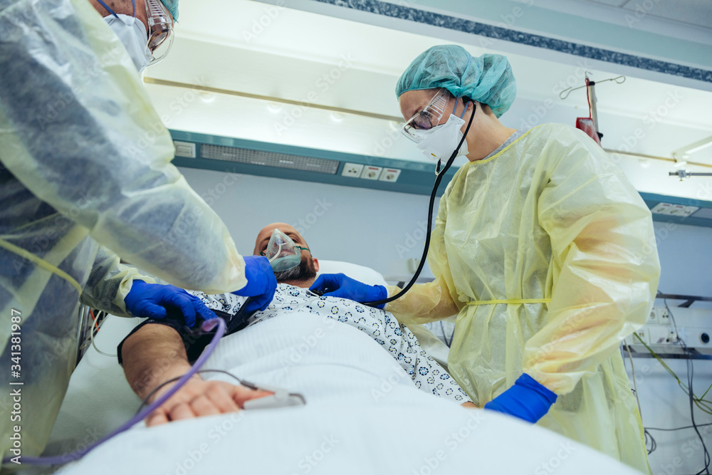 Doctors caring for patient in emergency care unit of a hospital with ...