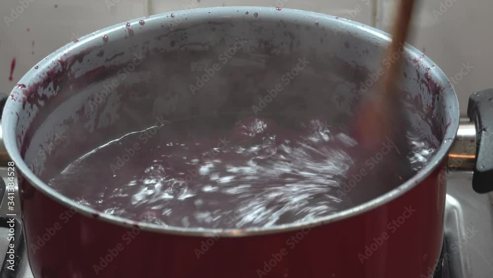 Cooking delicious red fruit jam, mixing and kneading. Close up ...