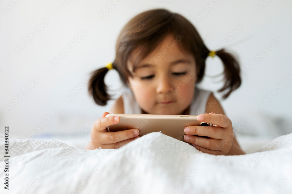 Hands of little girl lying on bed holding smartphone Stock Photo ...