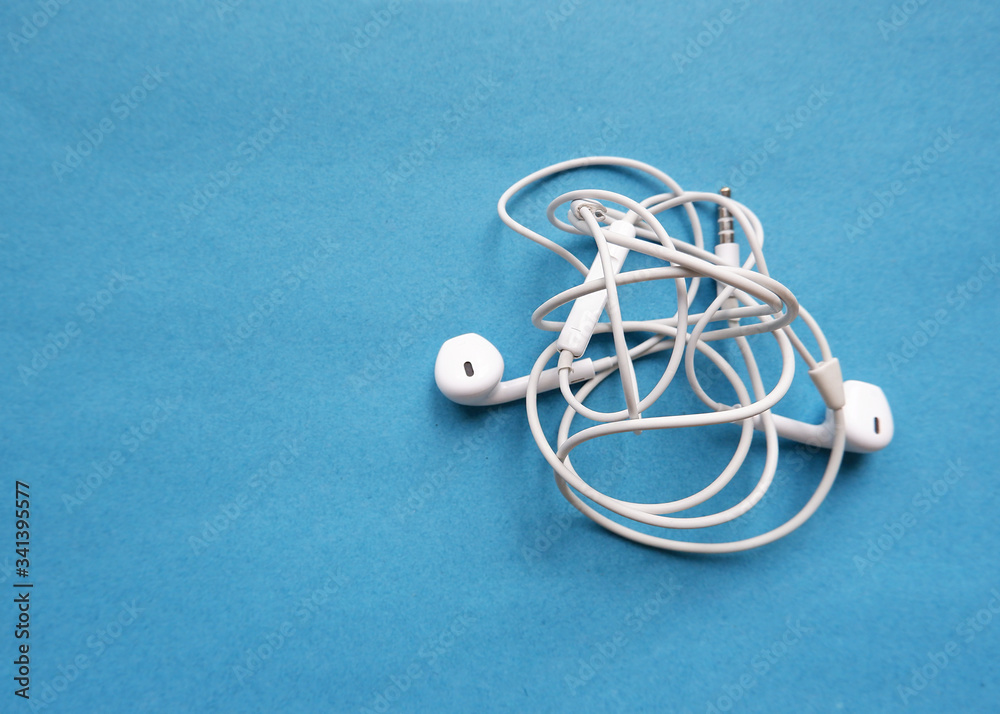 Tangled wired headphonTangled wired headphones on a blue background ...