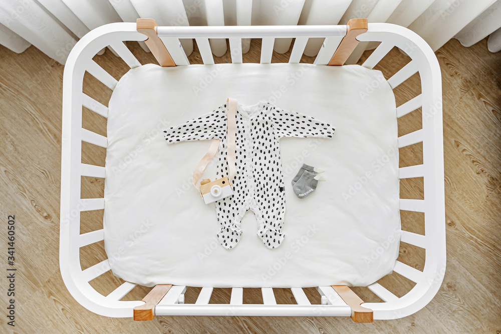 The top view of baby clothes and accessories in cot, cradle. Wooden ...