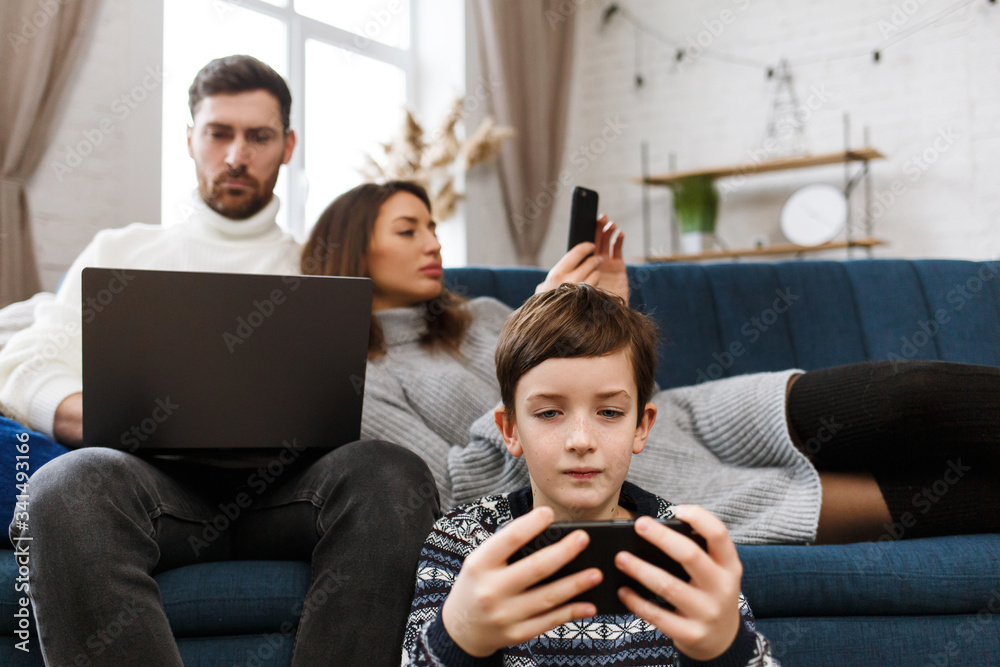Mother, father and son using laptop and mobile phones at home. Family ...