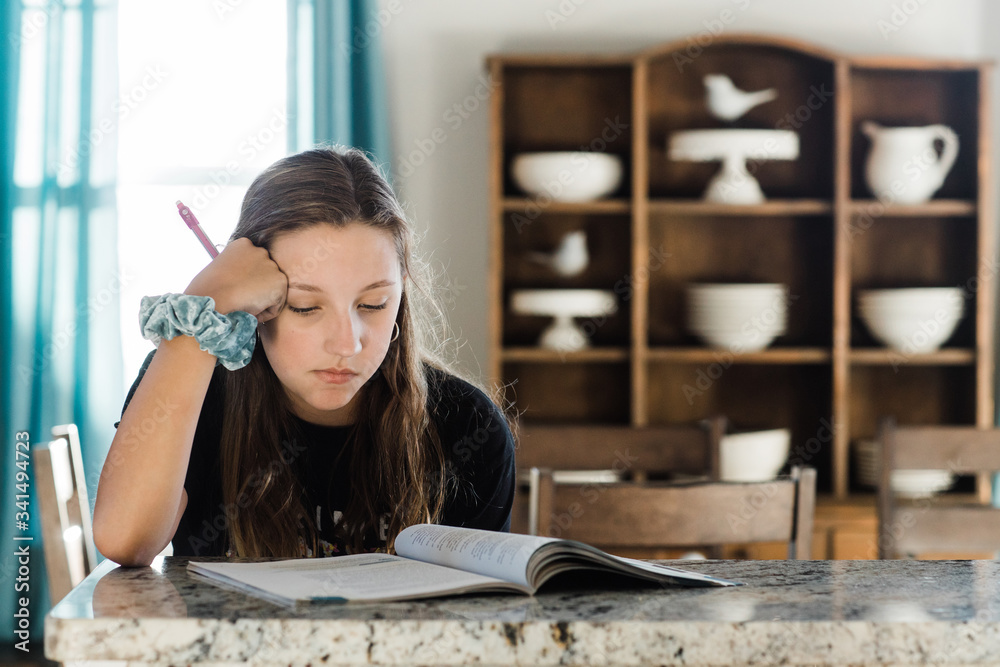 Teenage girl with long hair and scrunchie on her wrist studying and ...