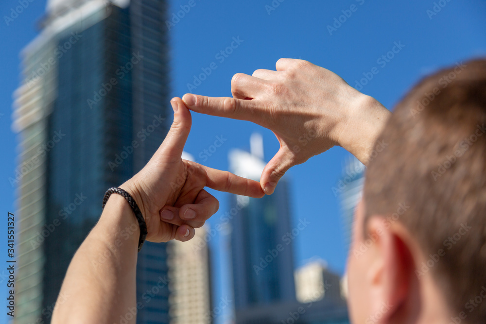 A man plans a future photo frame, makes a frame out of his fingers ...