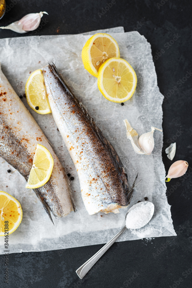 Fresh raw hake fillet on a black background. Fresh fish with lemon ...